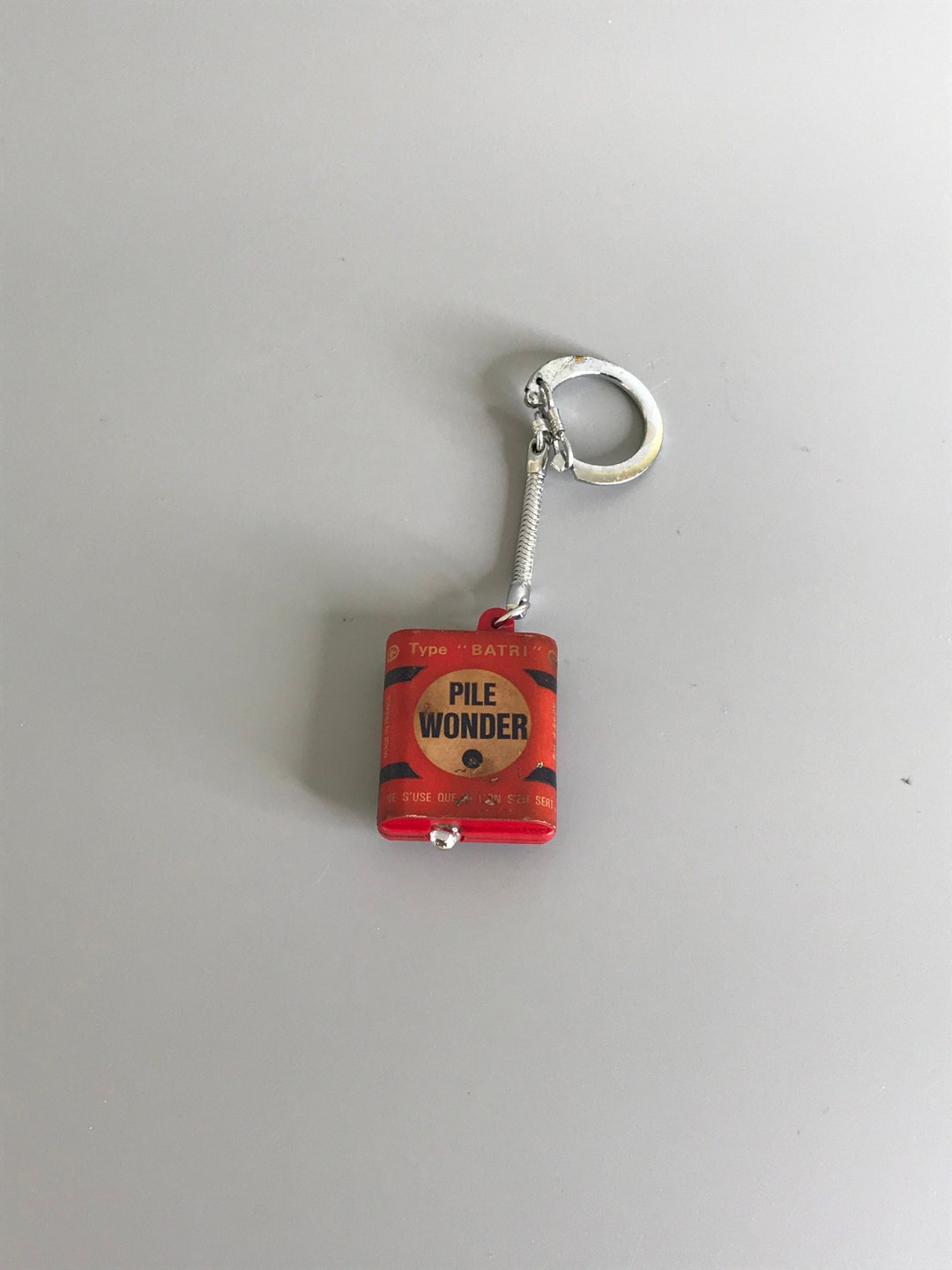 Französischer Vintage-Schlüsselanhänger mit Werbung für Pile Wonder ...