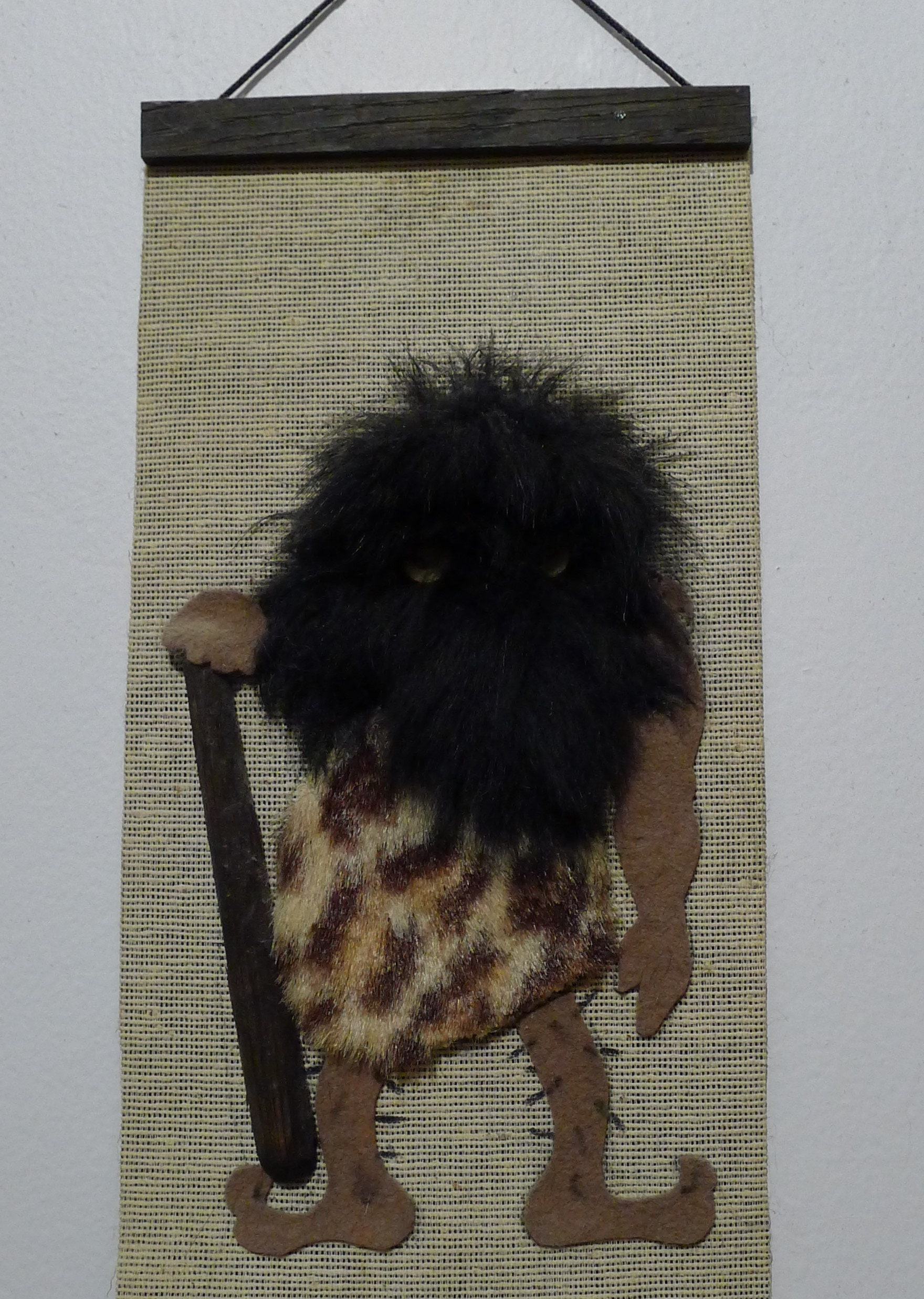 Friendly ancient wall hanging hairy caveman dressed in furs from the 60 ...