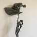 Man on Cliff Edge Holding a Hanging Woman Sculpture Wall Hanging Statue ...