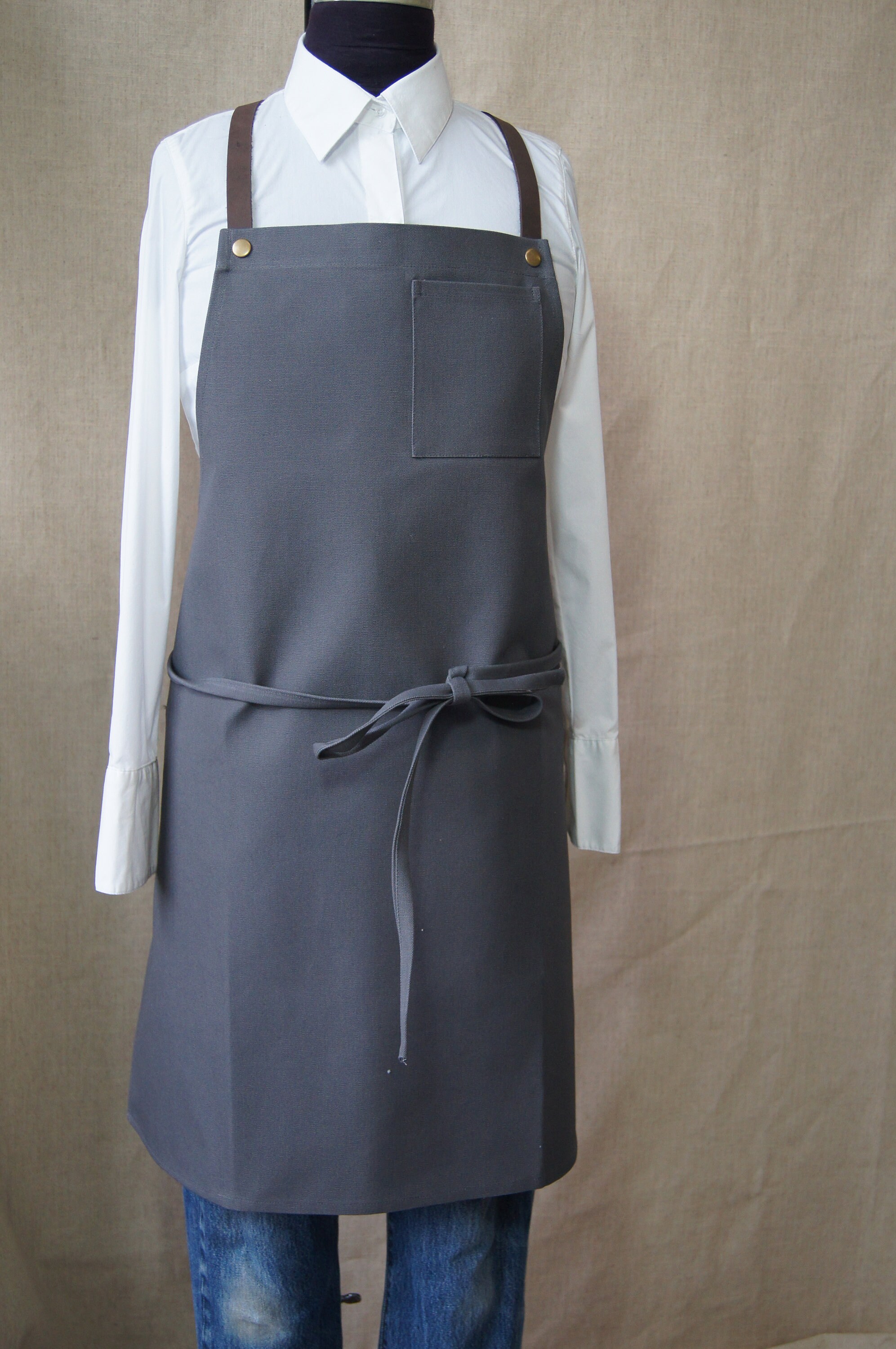 Apron with crossed leather straps at the back