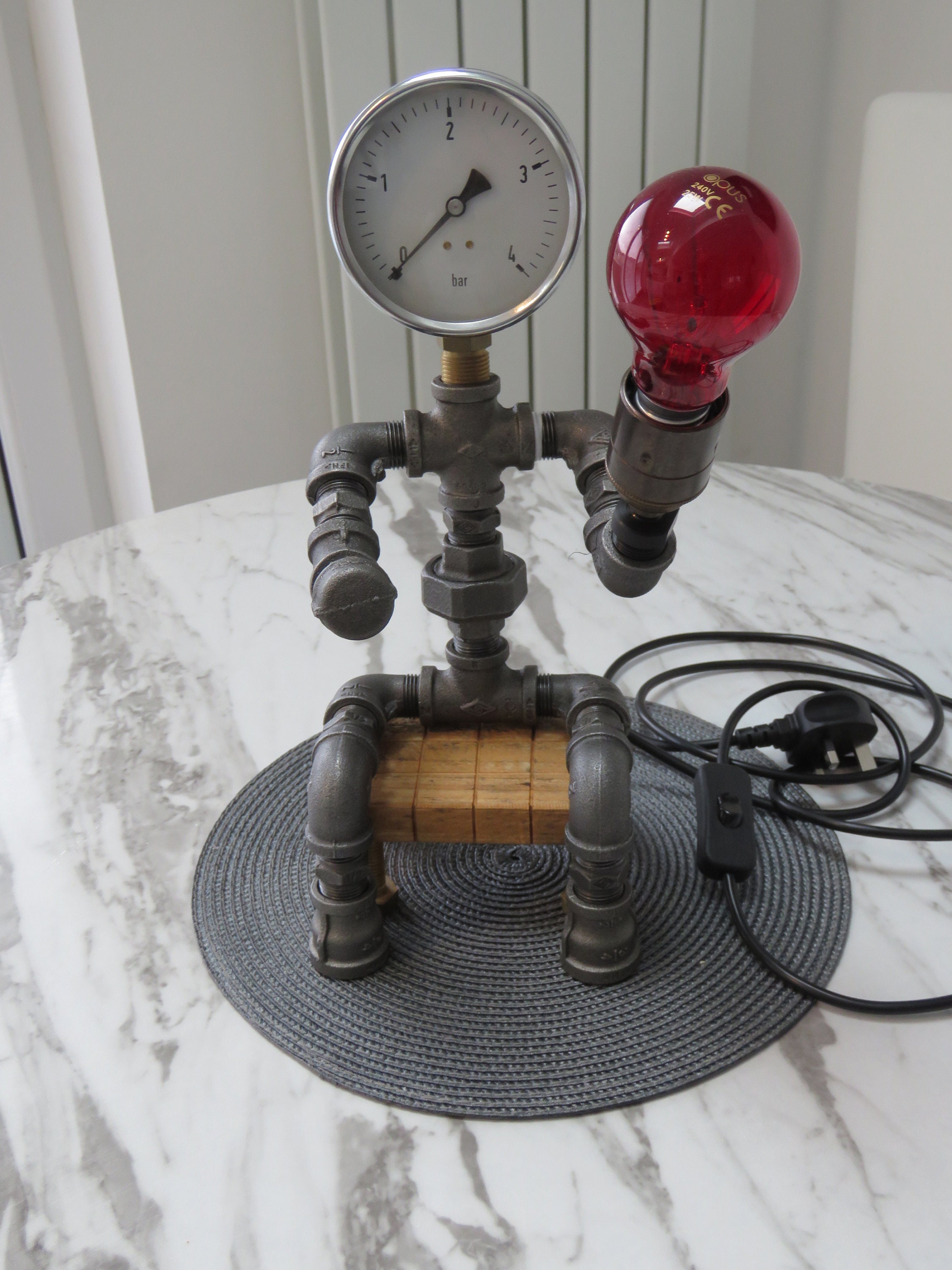 Pipelight Figure Sat on a Simple Wooden Bench Made From Industrial Pipe ...