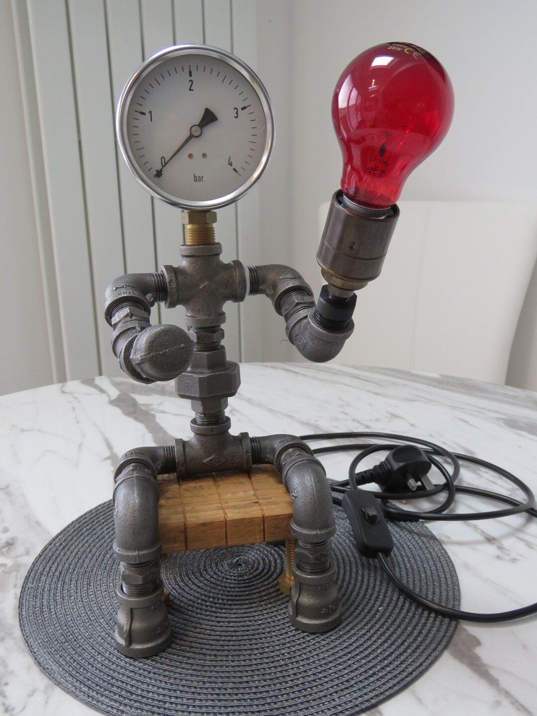Pipelight Figure Sat on a Simple Wooden Bench Made From Industrial Pipe ...
