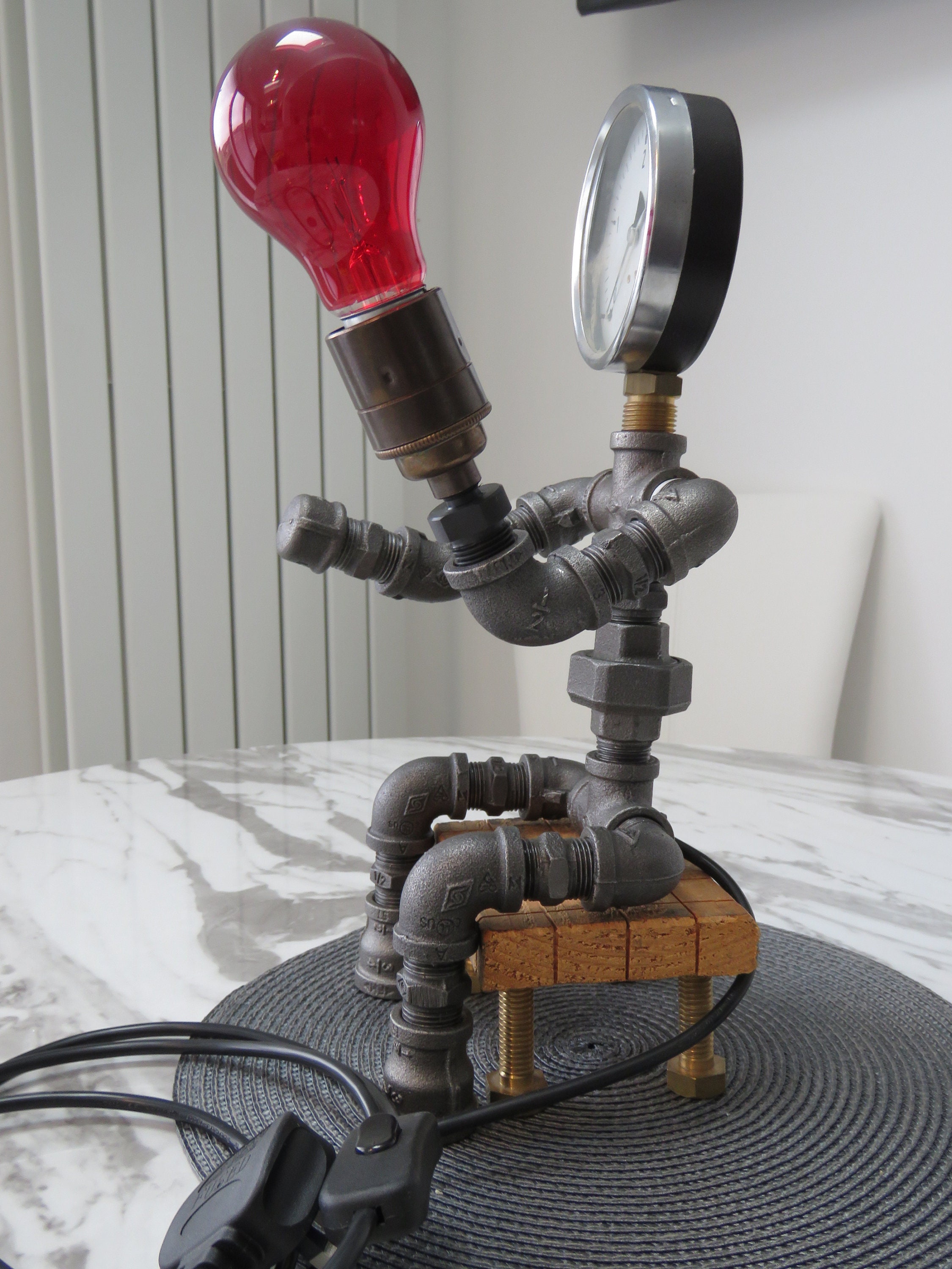 Pipelight Figure Sat on a Simple Wooden Bench Made From Industrial Pipe ...