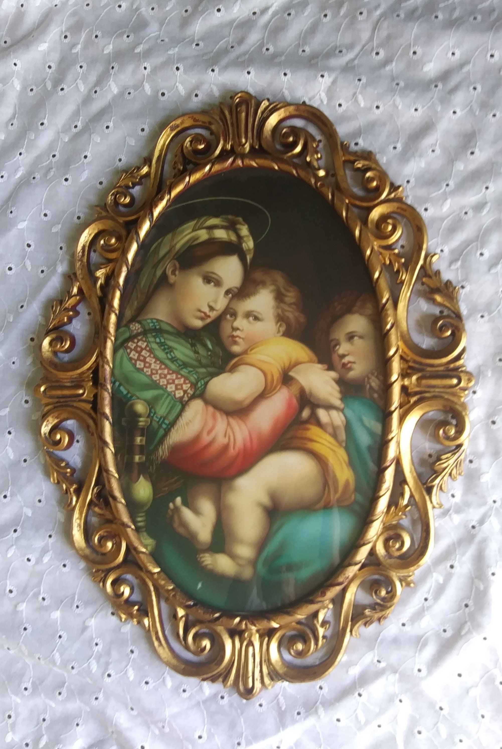 A vintage oval frame with the Madonna Virgin Mary figurine under a ...