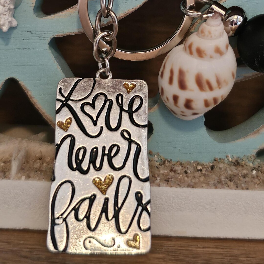 Keychain Featuring a "love Never Fails" Charm, Accented With Black and ...