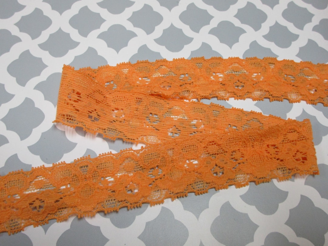 Este es un adorno de encaje elástico de pergamino de color naranja de ...