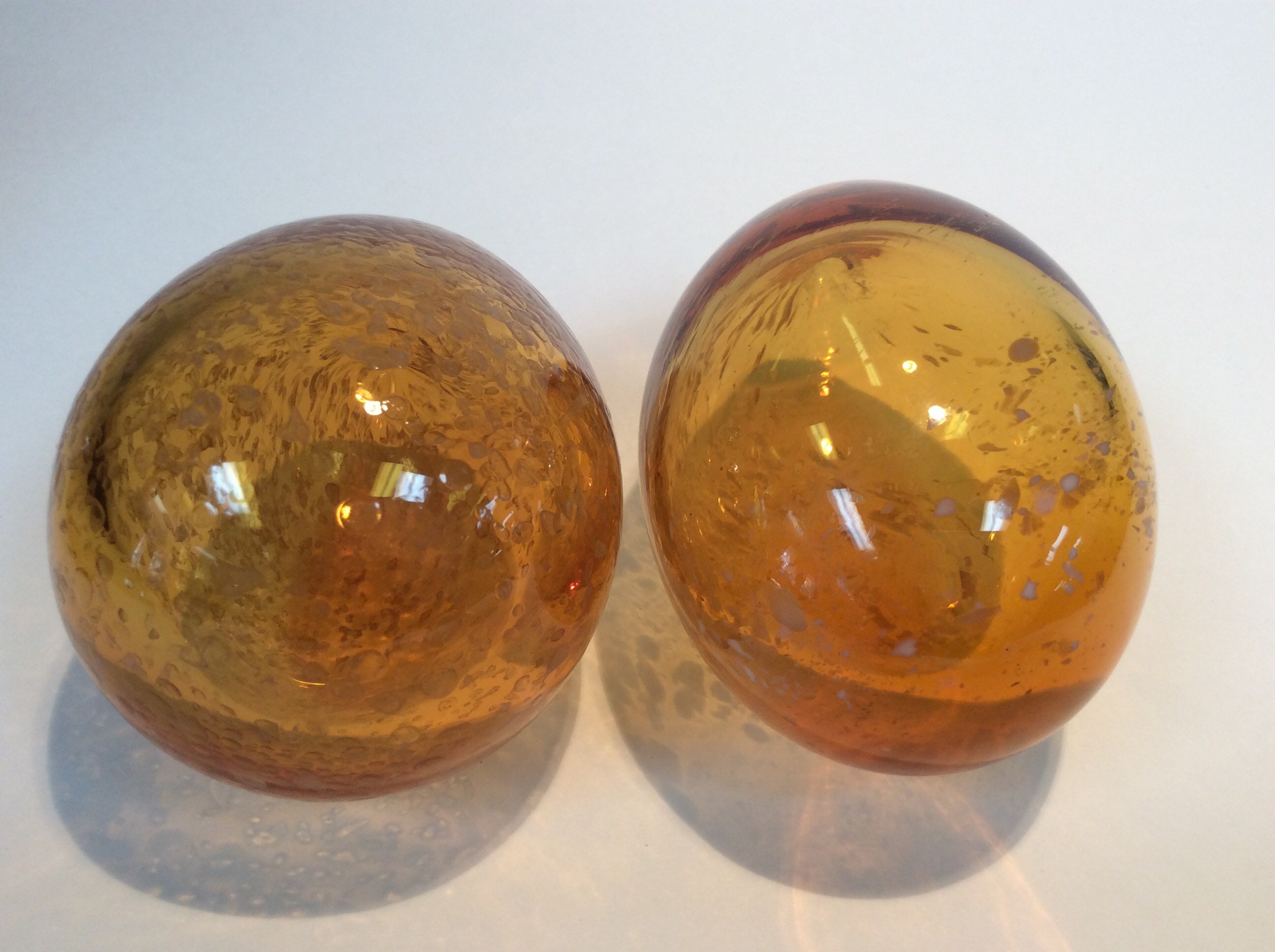 Pair Blenko Glass hand blown egg paperweights amber with white speckles.