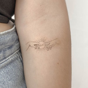 two hands reaching tattoo