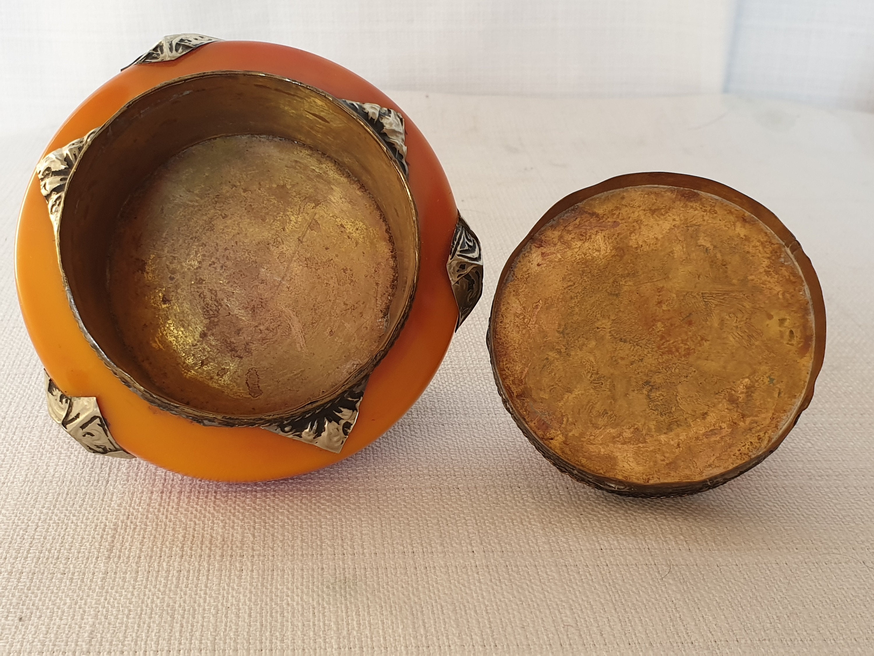 Two ornate orange lid jars, finished with brass ornaments.