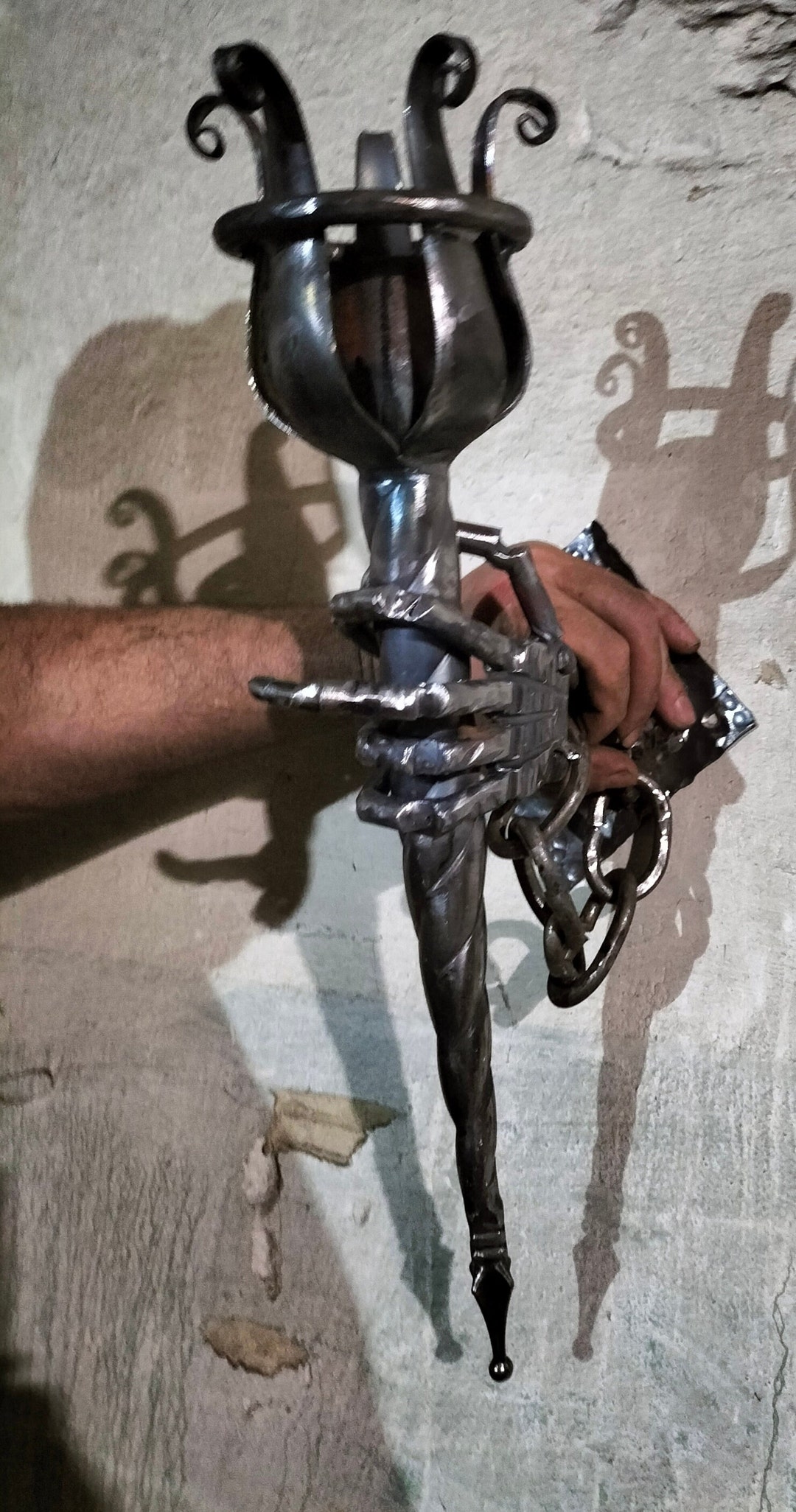 A Torch-shaped Metal Wall Lamp That Holds a Skeleton of a Human Hand ...