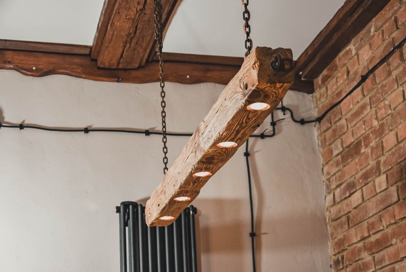 Een lange houten lamp met balk, hangend aan kettingen in rustieke stijl ...
