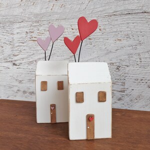 This White Wooden House Decorated With Two Pink Hearts is a Beautiful ...