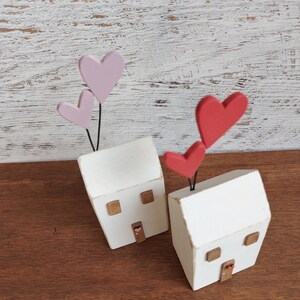 This White Wooden House Decorated With Two Pink Hearts is a Beautiful ...