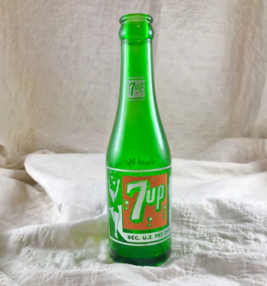 Green 7UP Bottle With Bubble Girl on Front Label Beside a White 7UP on ...