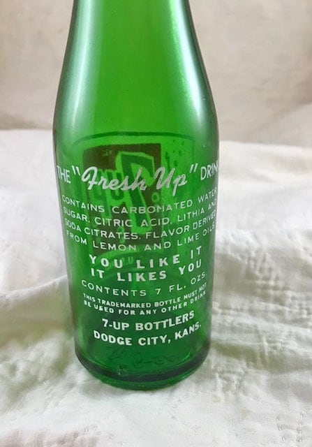 Green 7UP Bottle With Bubble Girl on Front Label Beside a White 7UP on ...