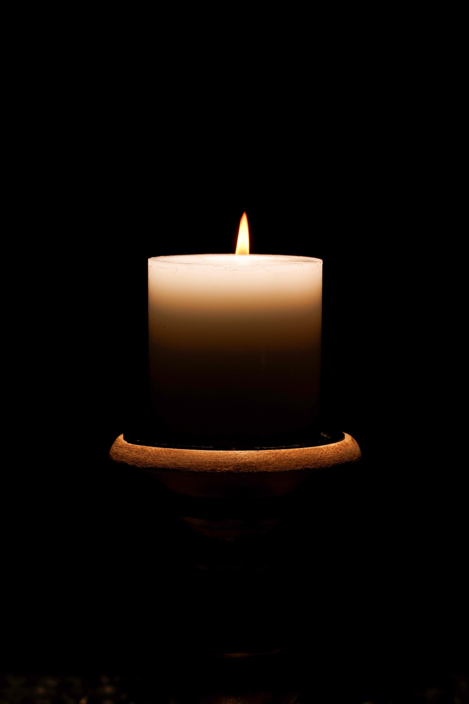 Single Lit Candle on a Small Wooden Holder in a Completely Dark Room ...