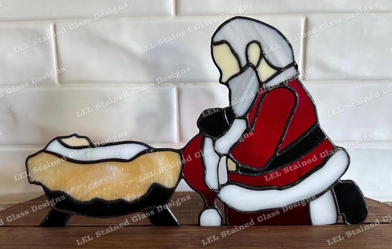 Santa Kneeling at Baby Jesus Manger With Background-stained Glass ...