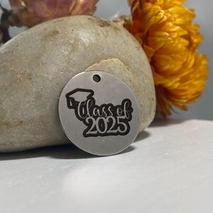 Clase de 2025 con birrete de graduación en dije redondo de acero ...