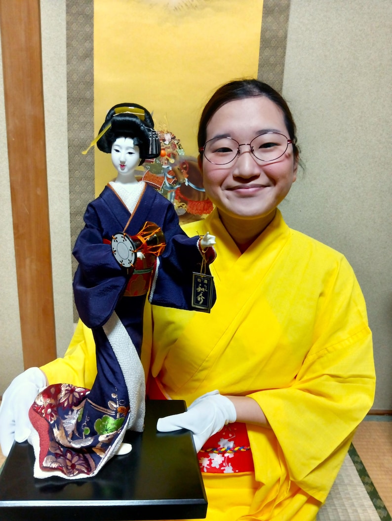 A Beautiful and Cute Geisha Doll. She is Wearing a Purple Kimono With ...