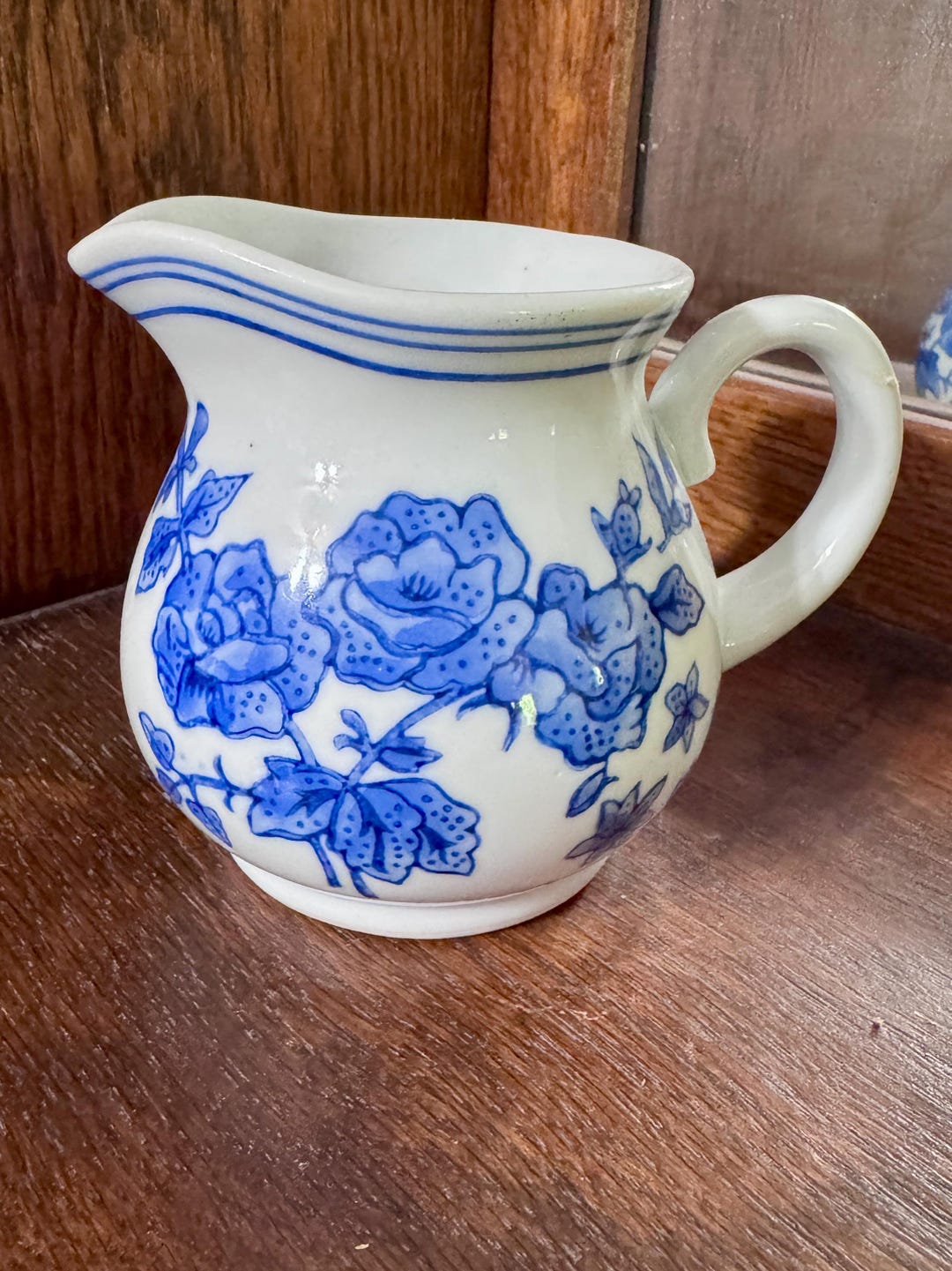 Small, White Ceramic Creamer Pitcher Adorned With Blue Floral Designs ...