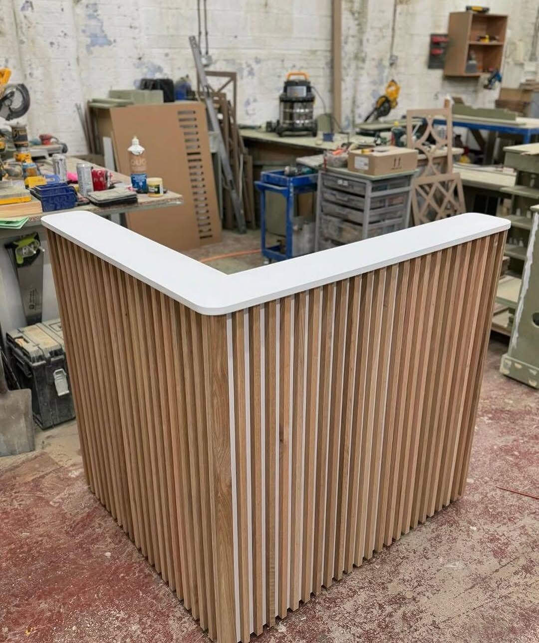 L-shaped Reception Desk With Vertical Wood Slats and White Countertop ...