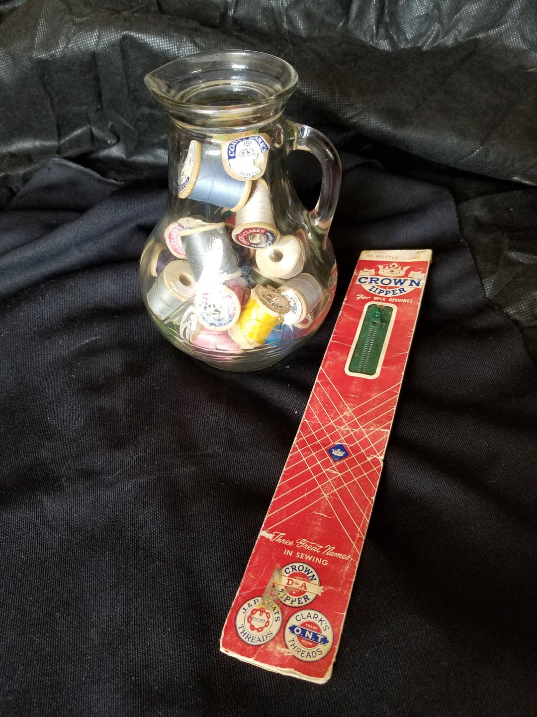 Crown Zipper and Wood Thread Spools in a Glass Pitcher With an Embossed ...