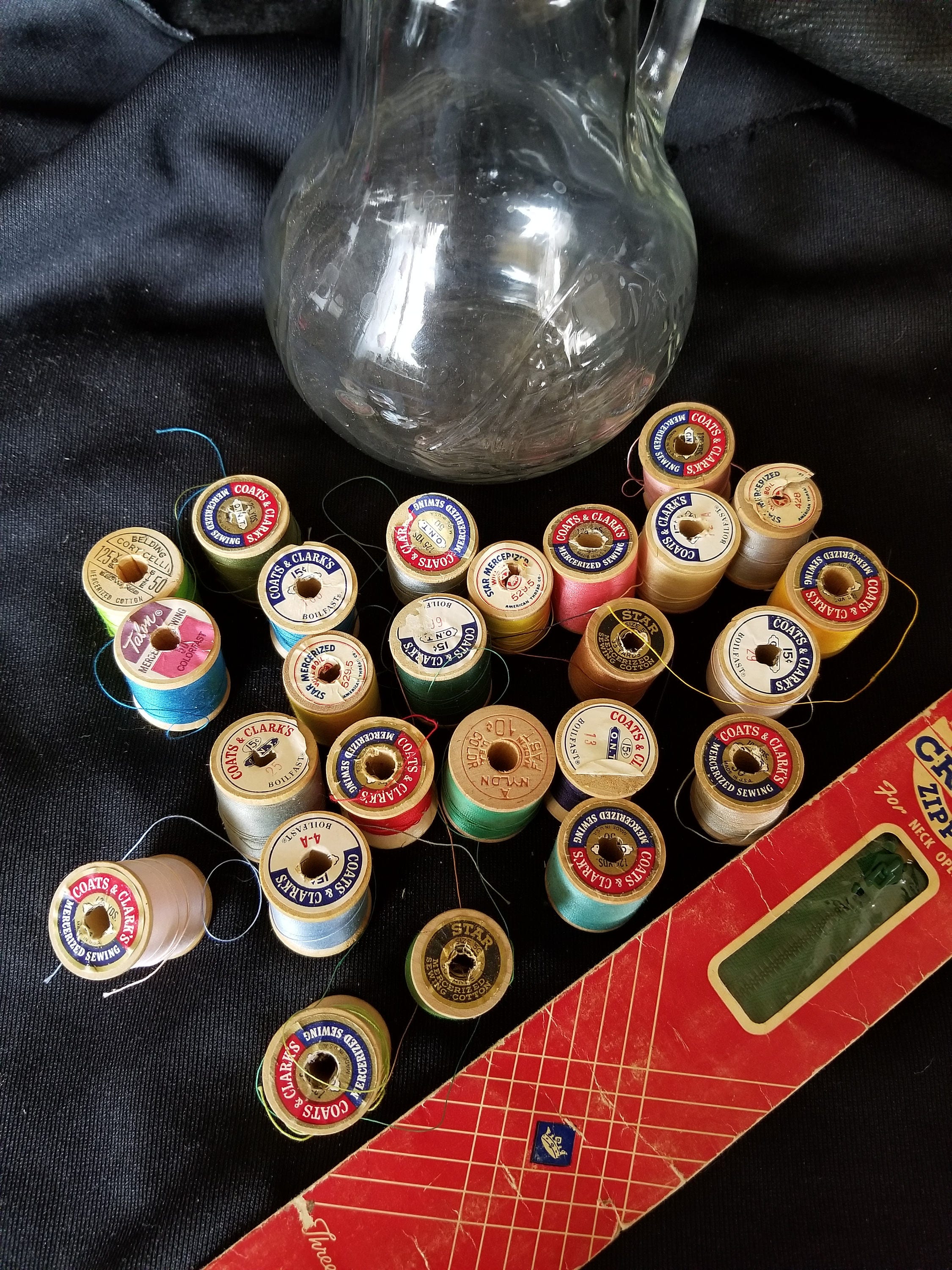 Crown Zipper and Wood Thread Spools in a Glass Pitcher With an Embossed ...