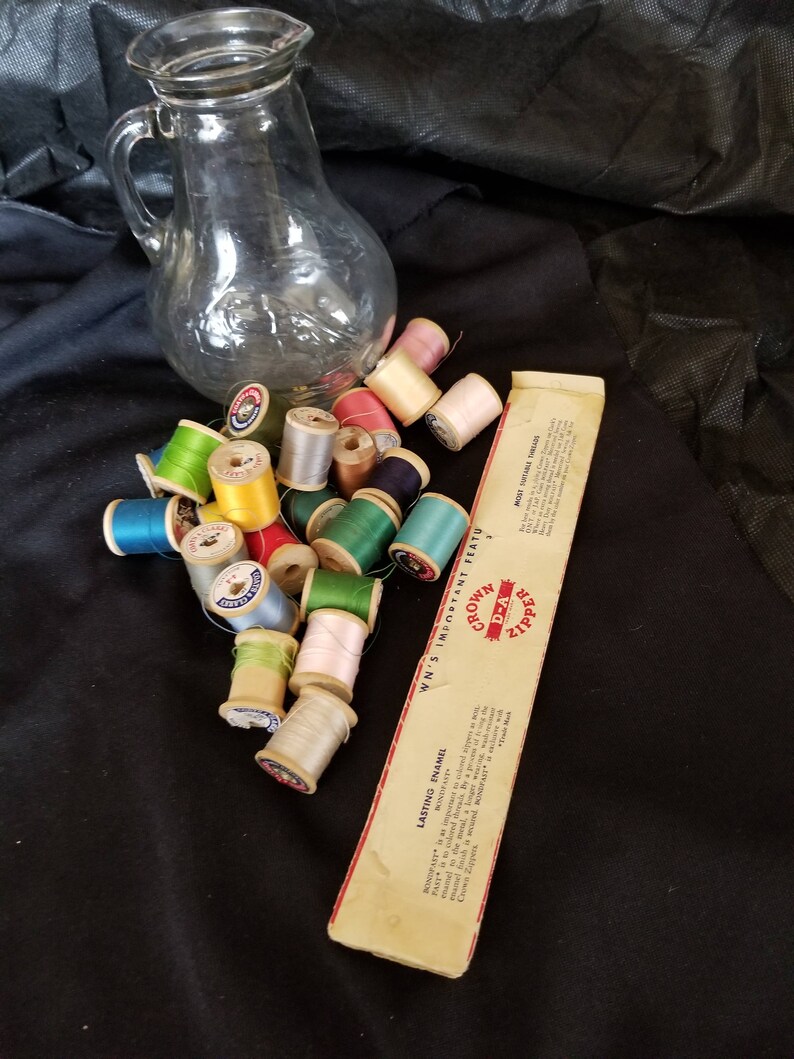 Crown Zipper and Wood Thread Spools in a Glass Pitcher With an Embossed ...