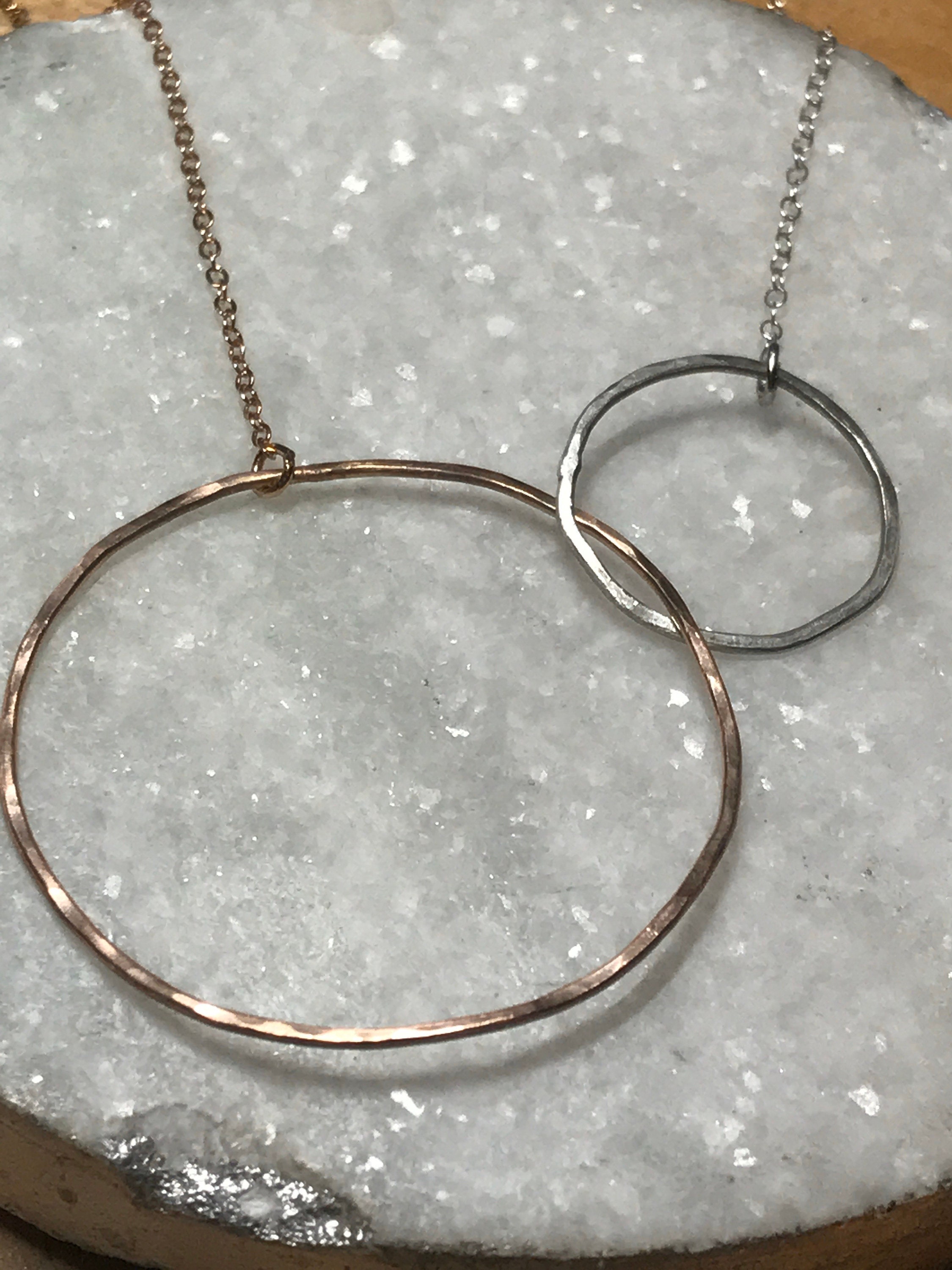 The Lydia necklace is two interlocking circles, one small silver and ...