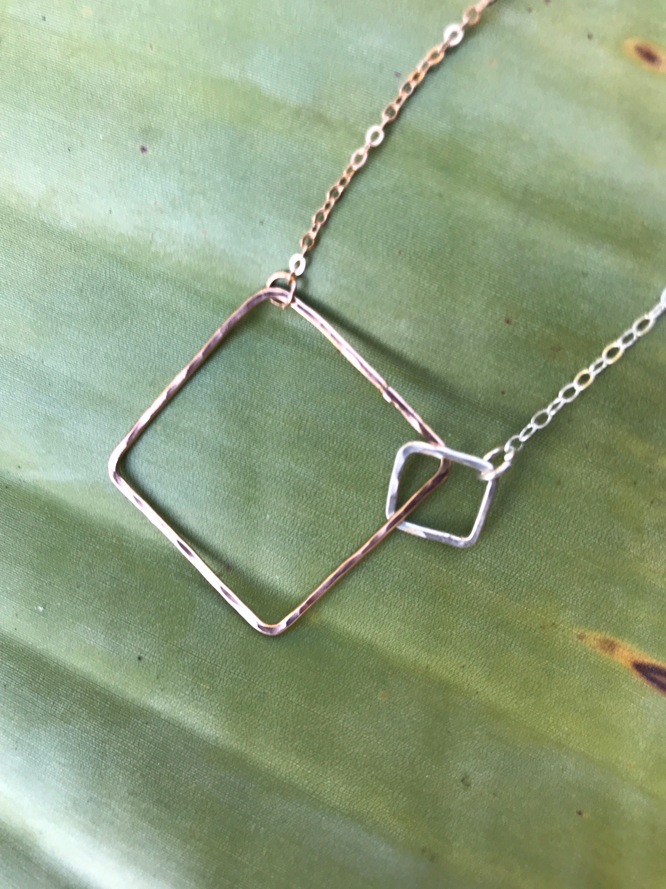 The Lydia necklace is two interlocking squares, one small silver and ...