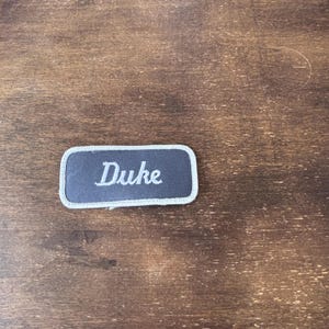Duke. A Gray Patch That Says "duke" in White Script With White Border ...