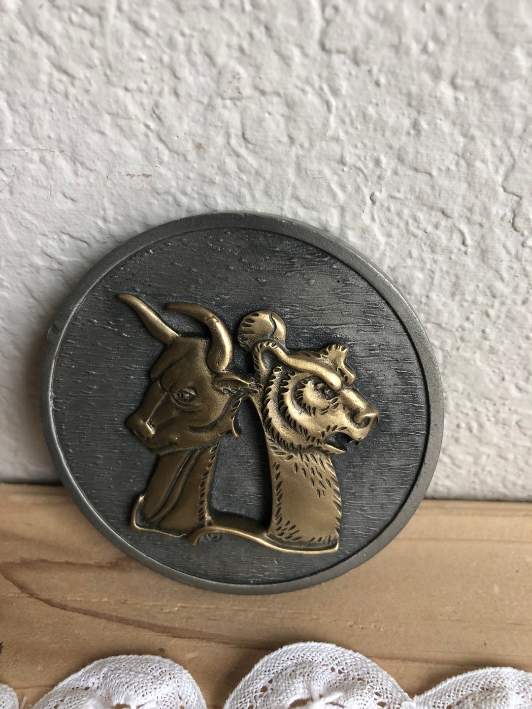 A Round Metal Paperweight With A Raised Bull and Bear Design With A ...