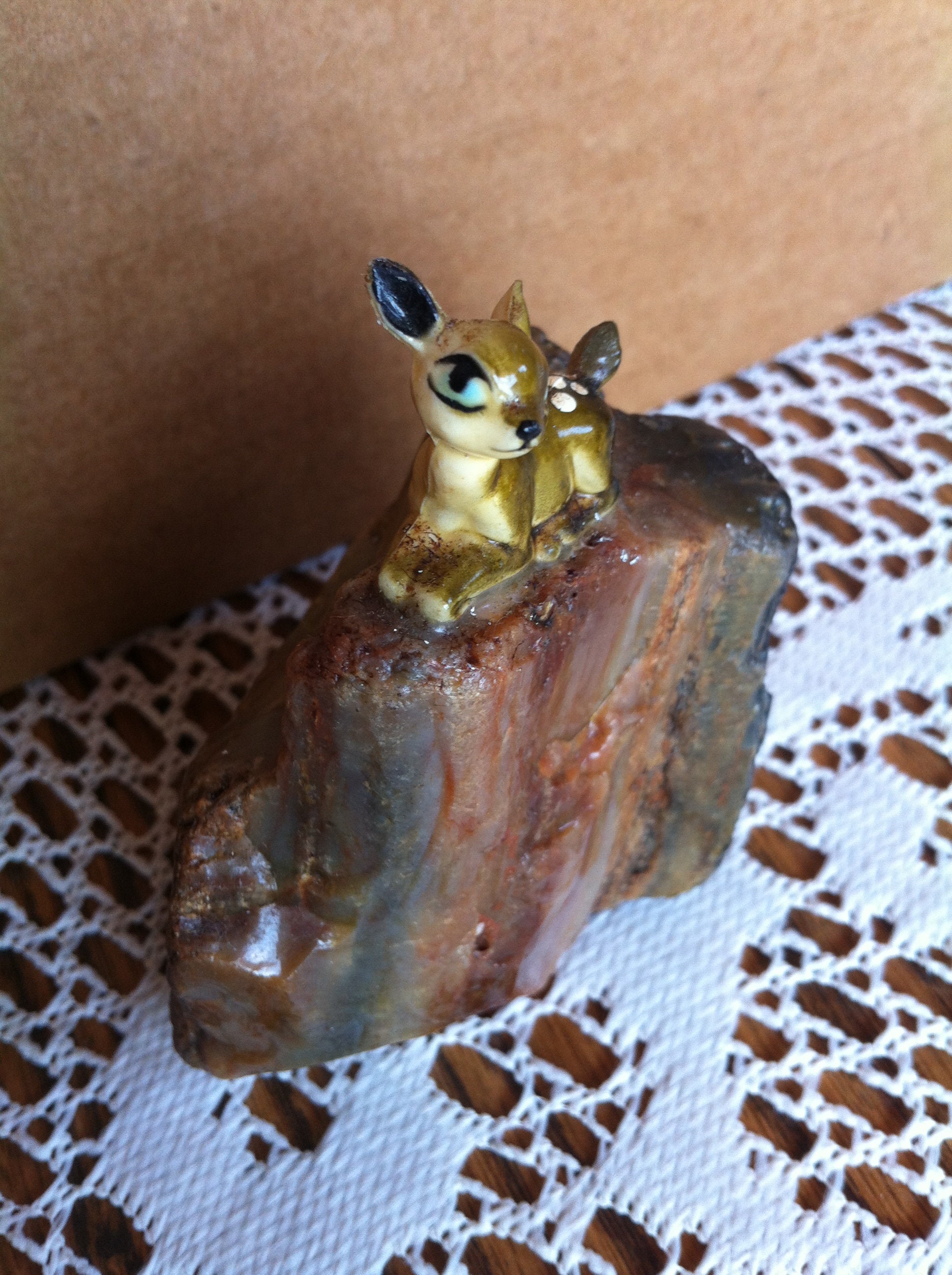 A Tiny Miniature Fawn Resting On Top Of A Shiny Rock Paperweight ...