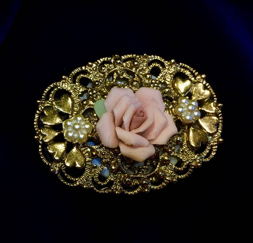 An Intricate Filigree Broach With a Ceramic Rose Bud Mounted on a Blue ...