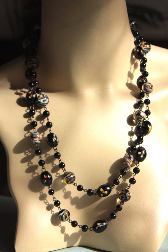 A long string of swirling, handmade glass beads with … - Gem