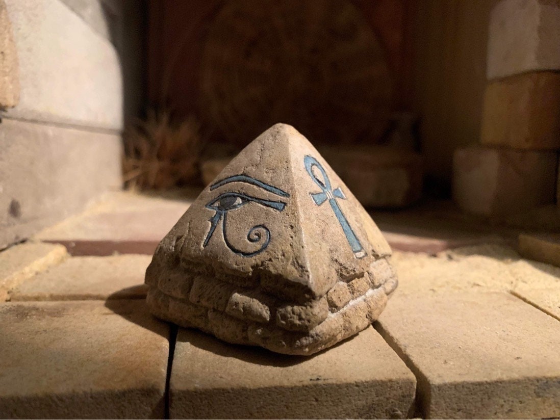 Egyptian pyramid featuring the eye of Horus, Ankh, Djed pillar, and Scarab