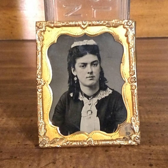 Antique tintype portraits were often framed in gold foil / gilt frames ...